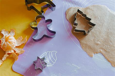 진저브레드 반죽에 크리스마스 쿠키 형태와 귤이 테이블 위에 놓여 있습니다 크리스마스 쿠키 만들기 크리스마스 배경입니다 새해 선물 계피 비스킷 준비 달콤한 음식 배경입니다