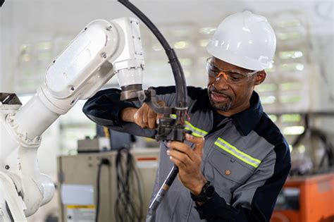 아프리카계 미국인 남성 엔지니어 작업자가 공장에서 자동 로봇 암 기계를 유지 보수합니다 스마트 팩토리에서 드라이버가 있는 검은