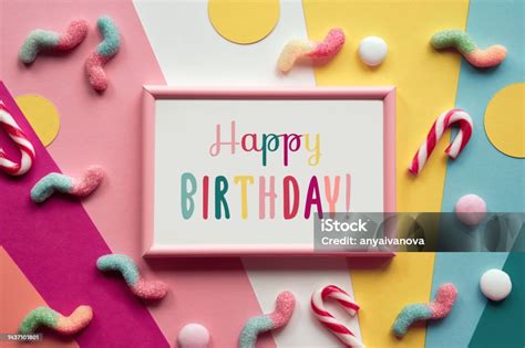 텍스트 생일 축하합니다 겹겹이 쌓인 색종이에 프레임에 프레임 주위에 다양한 과자 과자 초콜릿 및 사탕 지팡이 복사 공간이 있는 다채로운 인사말 디자인 생일에 대한 스톡 사진
