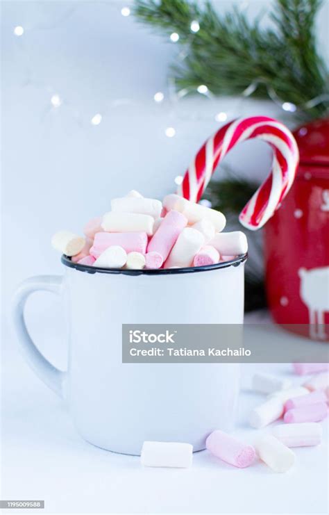 마시멜로와 크리스마스 과자가있는 흰색 컵 전나무 가지 공 및 크리스마스 조명이있는 흰색 배경에 배경에 사슴이있는 큰 빨간 항아리가 있습니다 0명에 대한 스톡 사진 및 기타