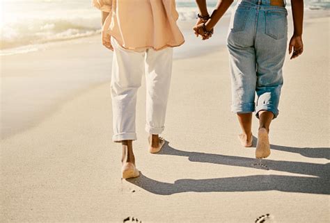 근접 촬영 커플은 모래 사장에서 맨발로 걷고 휴가 중에 신선한 공기를 함께 즐깁니다 여름 휴가 기간 동안 손을 잡고있는 동안 느리고 낭만적 인 산책을하는 남편과 아내의 낮은