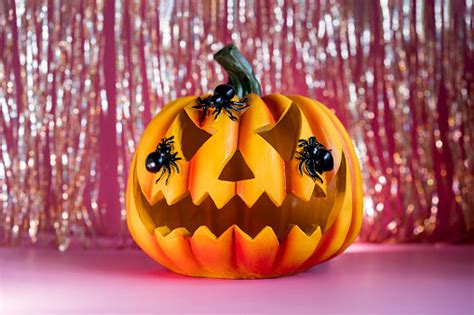 밝은 분홍색 할로윈 배경에는 오렌지 호박이 새겨져 있다 할로윈 잭오랜턴은 분홍색 배경에 빛나는 반짝이 커튼에 거미가 있다 해피 할로윈 장식 개념 선택적 초점 0명에 대한