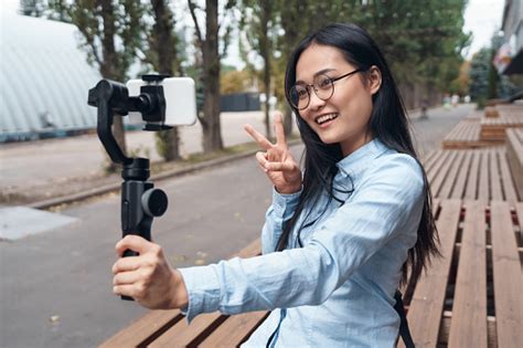 블로거 아시아 여자 서 에 거리 와 안정기 녹화 비디오 에 스마트 폰 보여주는 경례 제스처 에 카메라 장난 Monopod에 대한 스톡 사진 및 기타 이미지 Istock