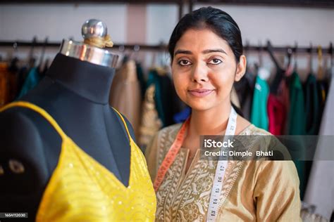 젊은 행복한 인도 여성 재단사 재봉사 마네킹이나 더미에 드레스 쇼케이스를 들고 서 있는 웃는 패션 디자이너 의류 작업장이나 스튜디오에서 측정 테이프를 들고 서 있다 근접