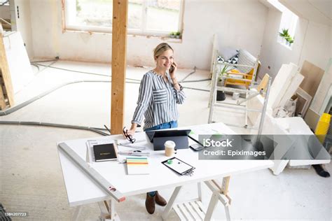 로프트에서 건설 현장에서 일하고 안경과 회색과 흰색 줄무늬 상단을 입고 높은 테이블 옆에 서있는 예쁜 젊은 건축가 다락방에 대한 스톡 사진 및 기타 이미지 Istock