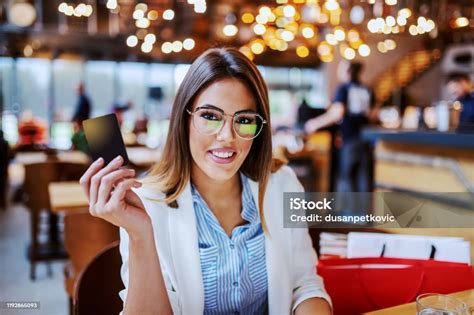매력적인 백인 유행 갈색 머리 와 아름다운 미소 들고 새로운 신용 카드 그녀는 단지 얻을 카페테리아 인테리어 배경에는 쇼핑 백이