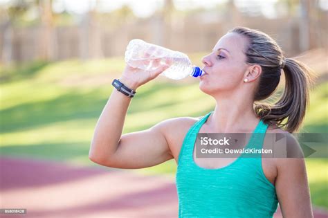 여성 피트 니스 선수는 그녀의 얼굴에 미소와 함께 물 물 병 들고 Track And Field Event에 대한 스톡 사진 및 기타 이미지 Track And Field