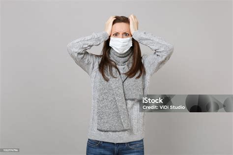 회색 스웨터에 젊은 여자 멸 균 얼굴 마스크와 스카프 스튜디오에서 회색 배경에 고립 된 머리에 손을 넣어 건강 한 라이프 스타일