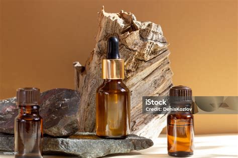 밝은 햇빛이 있는 베이지 색 배경의 로그 옆에 드롭퍼 스탠드가 있는 유리 화장품 병 천연 화장품 천연 에센셜 오일의 개념 0명에 대한 스톡 사진 및 기타 이미지 Istock