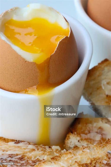 흰색 접시에 달걀 컵에 두 개의 부드러운 삶은 계란을 얹은 버터를 바른 토스트 군인의 전체 프레임 이미지 콧물 노른자를 얹은