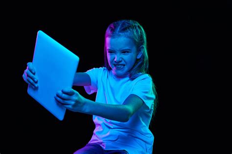 작은 아름다운 소녀 네온 불빛의 검은 스튜디오 배경 위에 격리된 태블릿에서 놀고 있는 흰색 티셔츠를 입은 아이의 초상화 8 9 살에 대한 스톡 사진 및 기타 이미지 Istock