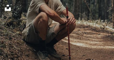 갈색 버튼 업 셔츠와 검은 모자를 쓴 남자가 갈색 마른 나뭇잎에 앉아 있다 사진 Unsplash의 무료 사람 이미지