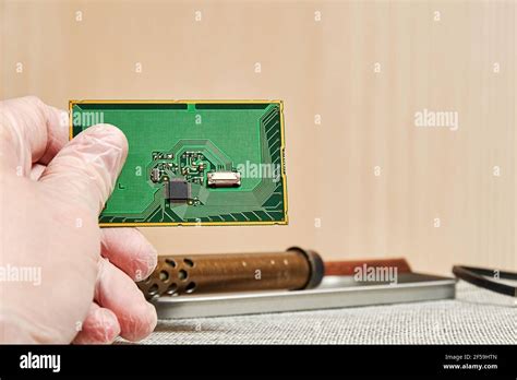 Engineer Analyzing PCB With A Chip In The Hand Over The Laboratory Table Manufacturing And