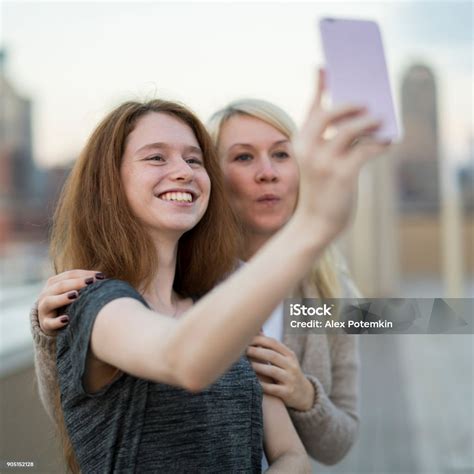 그녀의 여동생 16 년 오래 된 십 대 소녀 함께 놀고 스마트폰으로 Selfies 사진 촬영 및 옥상에서 재미와 젊은 꽤 임신한 여자 16 17 살에 대한 스톡 사진 및