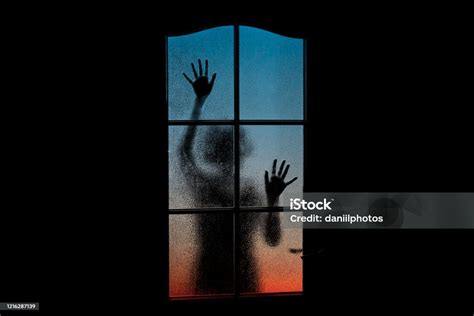 닫힌 유리 문 뒤에 밝은 배경에 고립 된 소녀 혼자의 어두운 실루엣 슬픔 슬픔 무관심 우울증 우울의 추상적 인 이미지 소녀는
