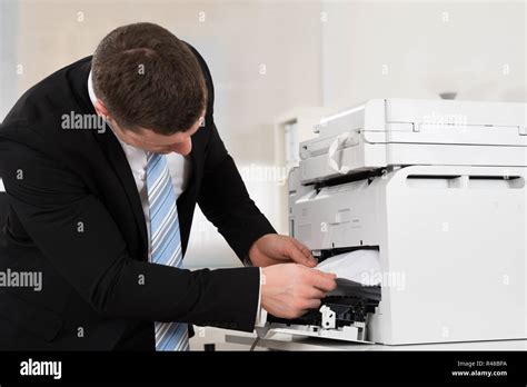 Businessman Removing Paper Stuck In Printer Stock Photo Alamy
