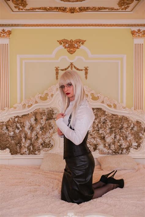 Человек одетый как девушка сексуальная белокурая секретарша представляя в ее спальне готовой для