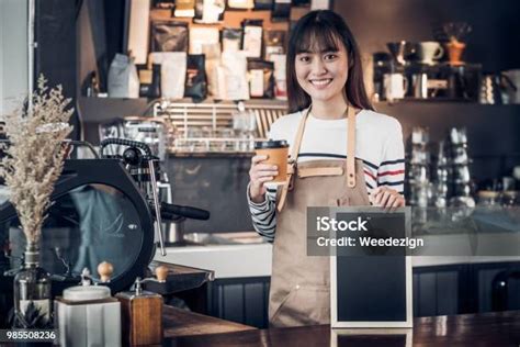 아시아 여성 바리 스타 착용 진 앞치마 미소 얼굴 카페 서비스 개념 비즈니스 소유자 시작 Upleave 공간에 텍스트를 추가 하기 위한 카운터 바에서 커피 컵과 빈 블랙