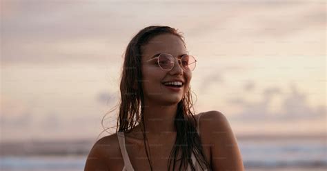 여름 해변에서 선글라스를 끼고 서핑 보드를 탄 서퍼 소녀 서핑 보드와 바다 일몰을 배경으로 한 아름다운 행복한 여자 사진