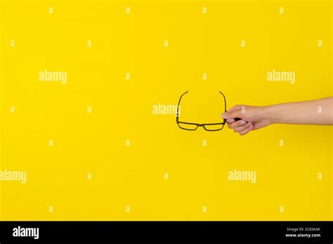 A Hand Holding Black Glasses Isolated Against The Colorful Background