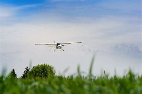 Small Plane Flying Over A Lush Green Landscape Of Trees And Grass Stock