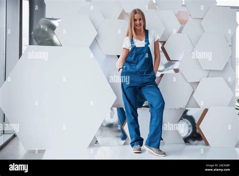 Reflection Of Wheel Girl In Blue Uniform Stands Against Abstract Wall With White Pieces Of