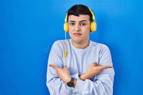 Non Binary Person Listening To Music Using Headphones Pointing To Both