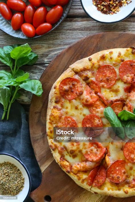 둥근 나무 도마에 슬라이스 페퍼로니 피자의 이미지 녹인 황금 버팔로 모짜렐라 치즈 풍부한 토마토 마리나라 소스와 신선한 바질 잎