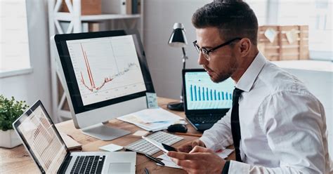 정장을 입은 젊은 사업가 스마트 폰을 사용 하 고 사무실에 앉아있는 동안 컴퓨터를 사용 하 여 데이터를 분석 하는 사진 Unsplash의 사업 이미지