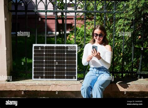 Happy Woman Connecting Smartphone To Photovoltaic Solar Panel