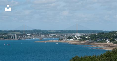 낮에는 흰 하늘 아래 푸른 바다를 가로지르는 흰색과 검은색 다리 사진 Unsplash의 무료 브레스트 이미지
