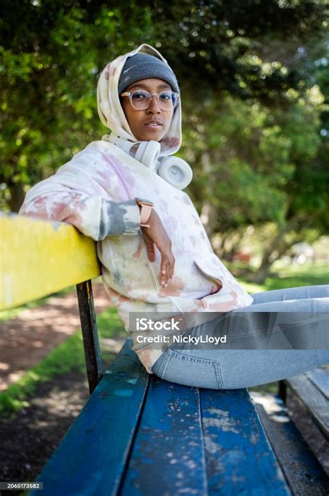 Portrait Of Confident Young African Girl Sitting On Park Bench Stock