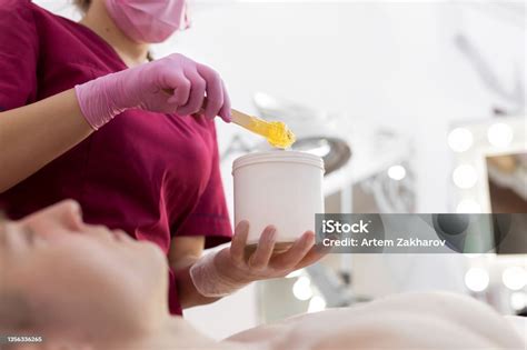 미용사는 항아리에서 설탕 페이스트를 취합니다 으르렁거리고 주걱으로 용기밖으로 설탕 페이스트 설탕 을 위한 설탕 페이스트 미용실에서 설탕을 섭취 개념에 대한 스톡 사진 및