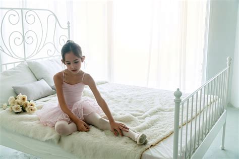 귀여운 분홍색 드레스 어린 소녀 9 년 집에서 침실에서 흰색 침대와 발레를 춤 발레 발레리나 어린 소녀는 방에서 발레 춤을 연습
