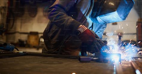 작업대에 기대어 보호 마스크를 쓴 젊은 용접공과 철 공작물 용접 사진 Unsplash의 무겁다 이미지