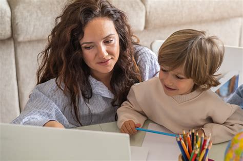 어린 아들의 숙제를 지도하고 집에서 편안하게 온라인 학습 및 교육 자료를 위해 노트북을 활용하고 연결과 성장을 촉진하는 어머니 2명에 대한 스톡 사진 및 기타 이미지