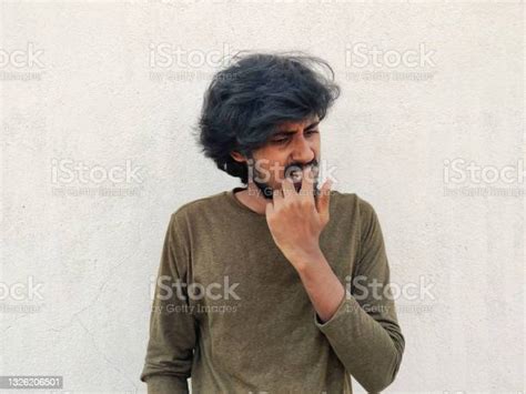 긴 머리를 가진 젊은 남부 인도 남자는 왼손 손가락 손톱을 물고있다 좌절 모드 흰색 배경 20 24세에 대한 스톡 사진 및 기타 이미지 Istock