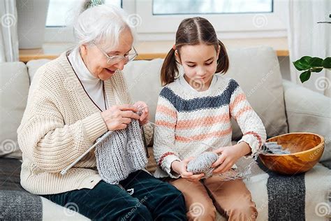 Nette Oma Die Zu Hause Auf Der Couch Ihre Enkelin Hilft Ihr Strickt