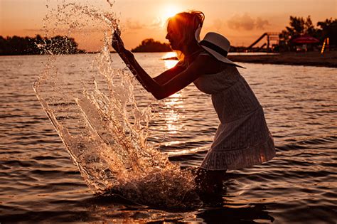 한 청녀가 물을 뿌려있다 여름 드레스와 일몰과 해변의 배경에 리본이달린 밀짚 모자를 입은 아름다운 행복한 금발의 실루엣 사진 강에 대한 스톡 사진 및 기타 이미지 Istock