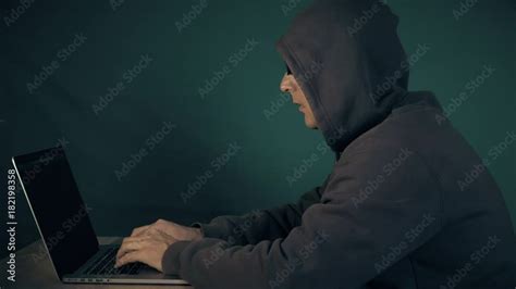 Programmer In Hood And Glasees Typing On Keyboard Of Laptop Computer