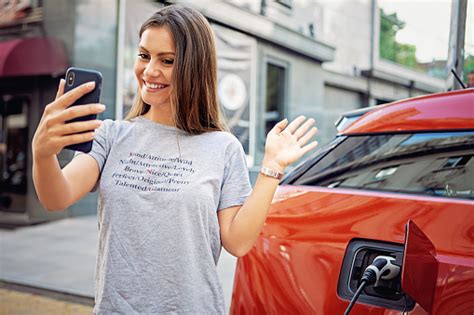 젊은 여자는 셀카를 복용 그녀의 전기 자동차를 충전 할 때까지 화상 통화를 만들기 셀카에 대한 스톡 사진 및 기타 이미지