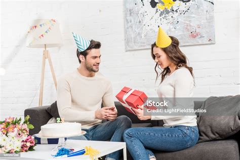 거실에 여자에 게 생일 선물 상자를 제시 하는 사람과 생일을 축 하 하 커플 개인 장식품에 대한 스톡 사진 및 기타 이미지