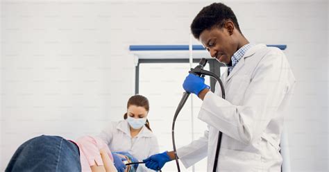 젊은 아프리카계 미국인 남자 의사와 여성 간호사가 여성 환자를 위해 내시경 절차를 하고 있으며 클리닉의 현대 검사실에서 소파에 누워 있다 사진 Unsplash의 내부 이미지