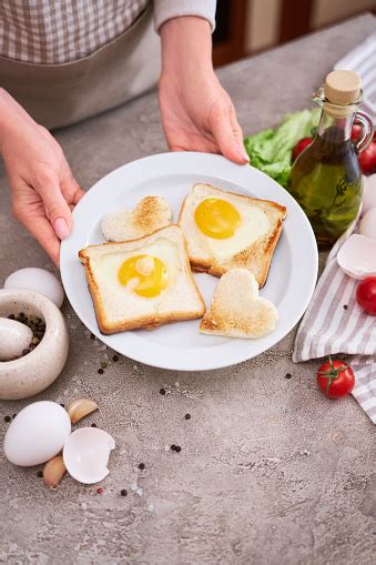 Woman Pits Plate With Fried Egg On Toast Bread On Concrete Table For