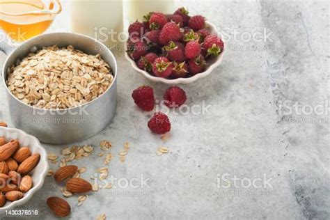 회색 콘크리트 오래된 테이블 배경에 귀리 우유 라스베리 꿀 및 아몬드가있는 오트밀 또는 그라놀라를 요리하기위한 재료 건강한 아침