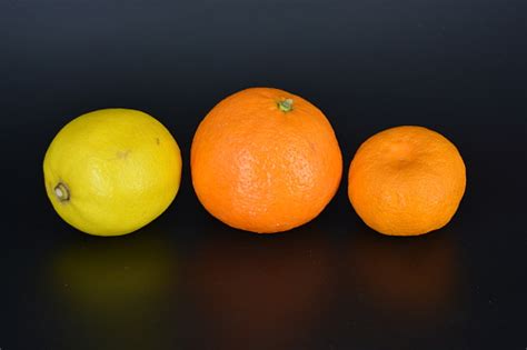 신선한 밝은 과일 노란 레몬 한 개 작은 오렌지 만다린 하나의 큰 미네랄로는 검은 색 플라스틱 배경에 놓여 있습니다 매일 맛있고 달콤한 과일 과일 꽃병 건강한 음식 0명에