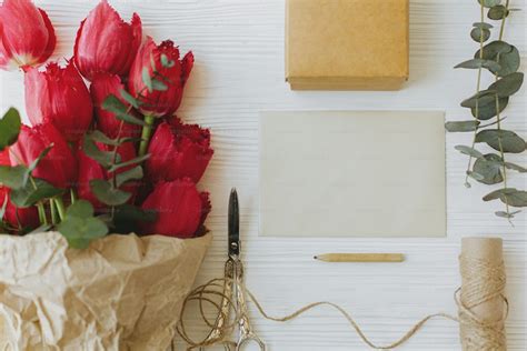 행복한 어머니의 날 인사말 카드 선물 연필 가위 소박한 흰색 나무 배경에 꼬기가 있는 공예 종이에 아름다운 빨간 튤립 행복한 여성의 날 인사말 카드 템플릿 사진