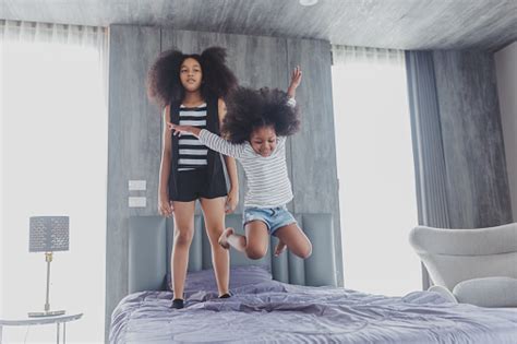 귀여운 어린 아이들이 홈에서 침대에서 뛰어 내립니다 집에서 행복한 가족 자매는 침대에 뛰어 올라 웃었다 2 3 살에 대한 스톡 사진 및 기타 이미지 Istock