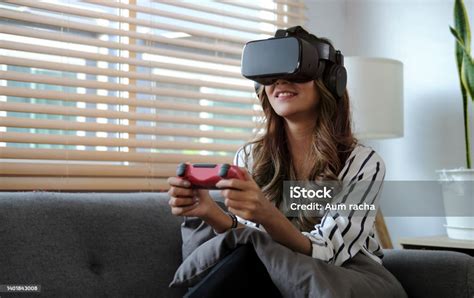 가상 현실 헤드셋을 착용하고 집에서 비디오 게임을하는 조이스틱을 들고 흥분한 밀레니엄 세대 여성 25 29세에 대한 스톡 사진 및 기타 이미지 Istock
