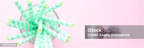 분홍색 배경에 투명한 유리 작은 병에 파티를 위한 흰색과 녹색 마시는 빨대의 종이 더미가 흐릿해졌습니다 텍스트 공간을 사용할 수 있습니다 배너 0명에 대한 스톡 사진 및